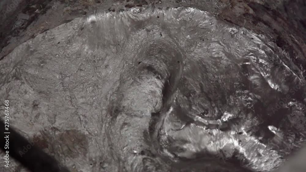 Mercury being stirred in a tank. The liquid metal forms waves and the ...