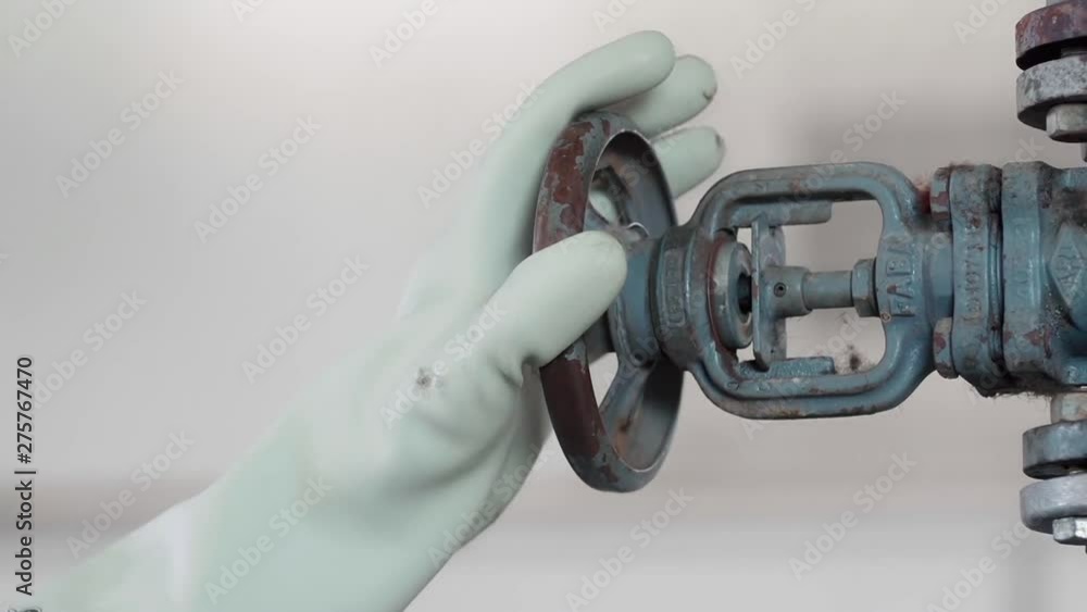 Industrial iron valve being opened by rubber gloved hand. Rotary valve ...