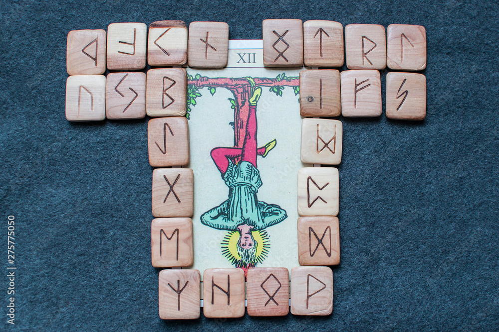 Magical runes for fortune telling and a tarot card Hanged man on a gray ...
