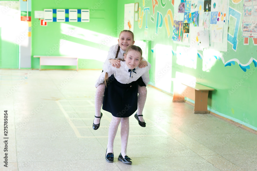 School friends at recess. A tall girl rolls her friend in her lap A ...