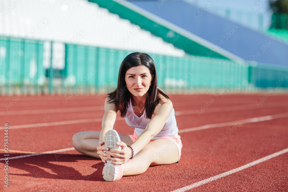 Young woman athlete brunette in pink shorts and tank tops on stadium ...