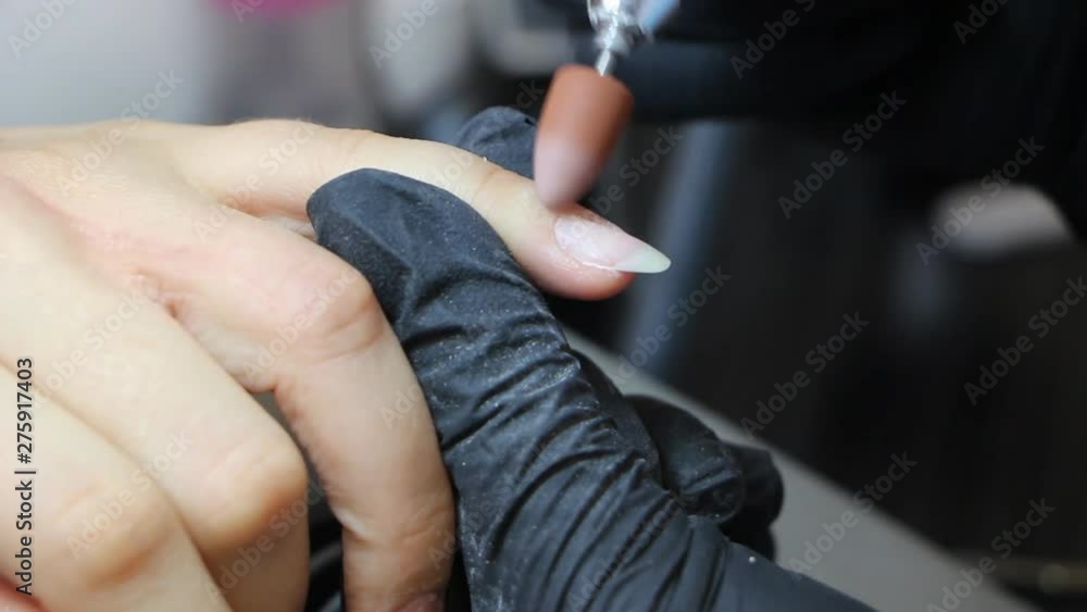 Manicurist is polishing cuticle and skin around nails by drill machine ...