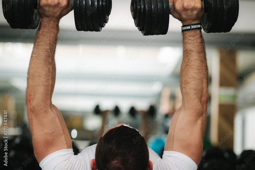 Male bodybuilder trains in the gym. He use dumbbells Stock Photo ...