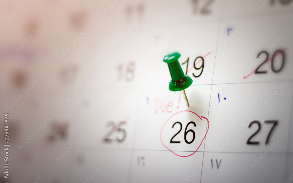 Due date of payment written on a calendar with a green push pin to ...