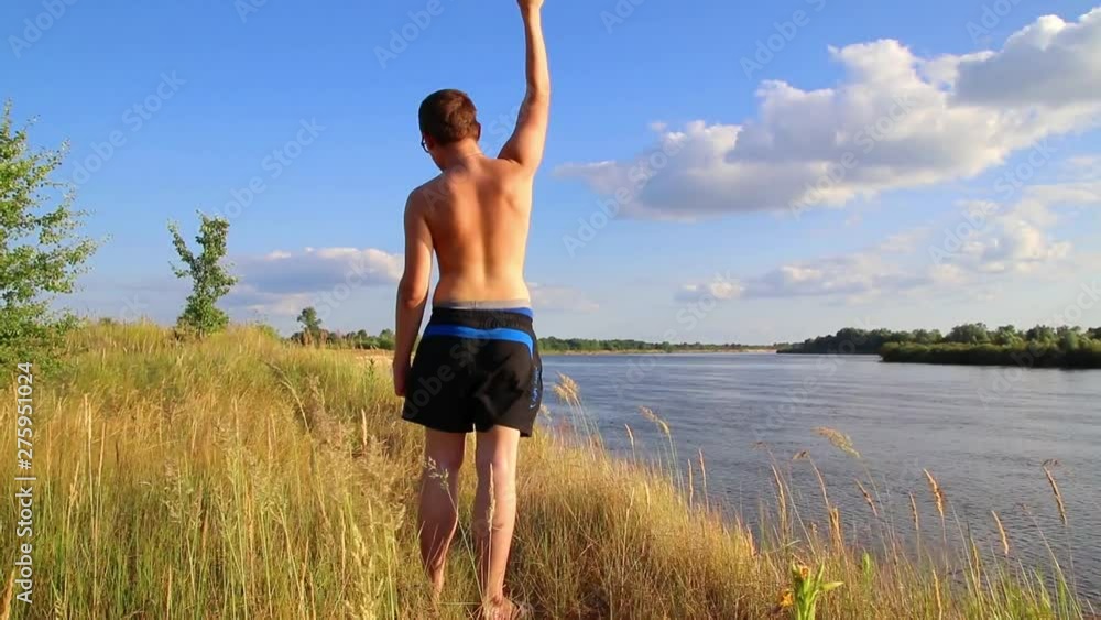 Bodybuilding by the river, a young man trains in the fresh air, an ...