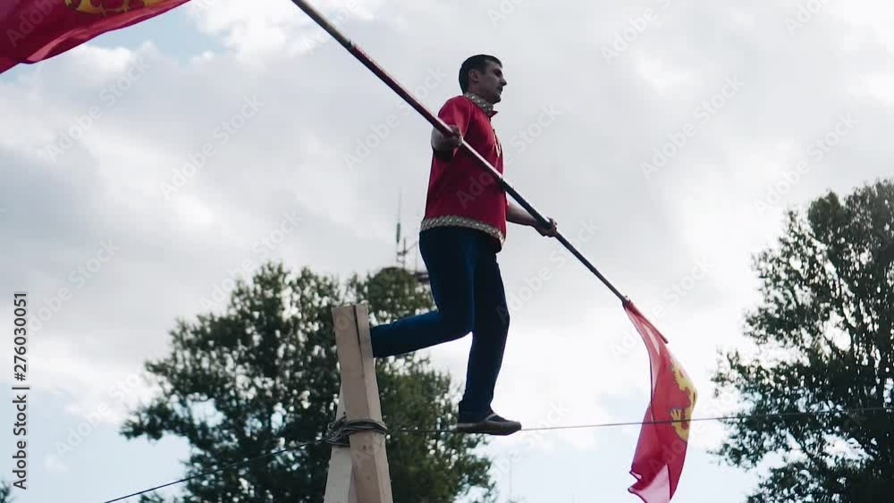 A man with a pole runs and jumps on the rope above the ground. Very ...