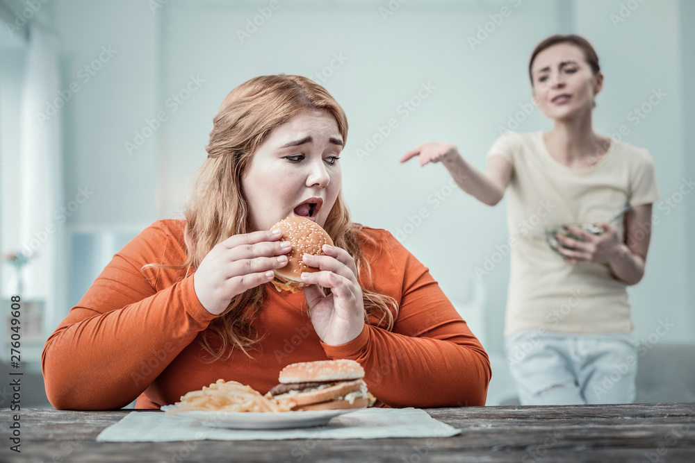 Emotional girl being afraid to eat fast food Stock Photo | Adobe Stock