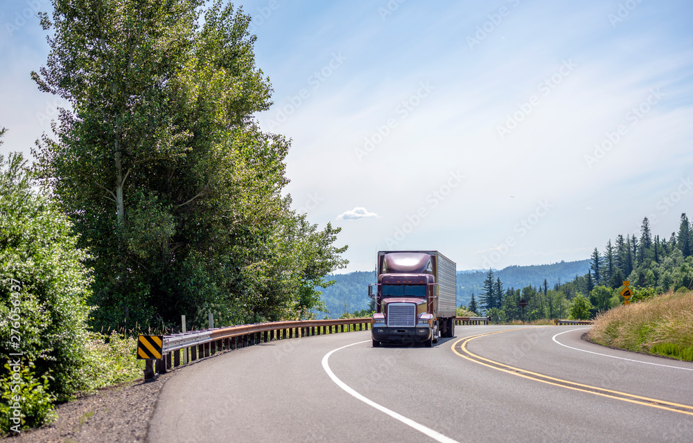 Big rig dark classic semi ruck with semi trailer moving on the turning ...