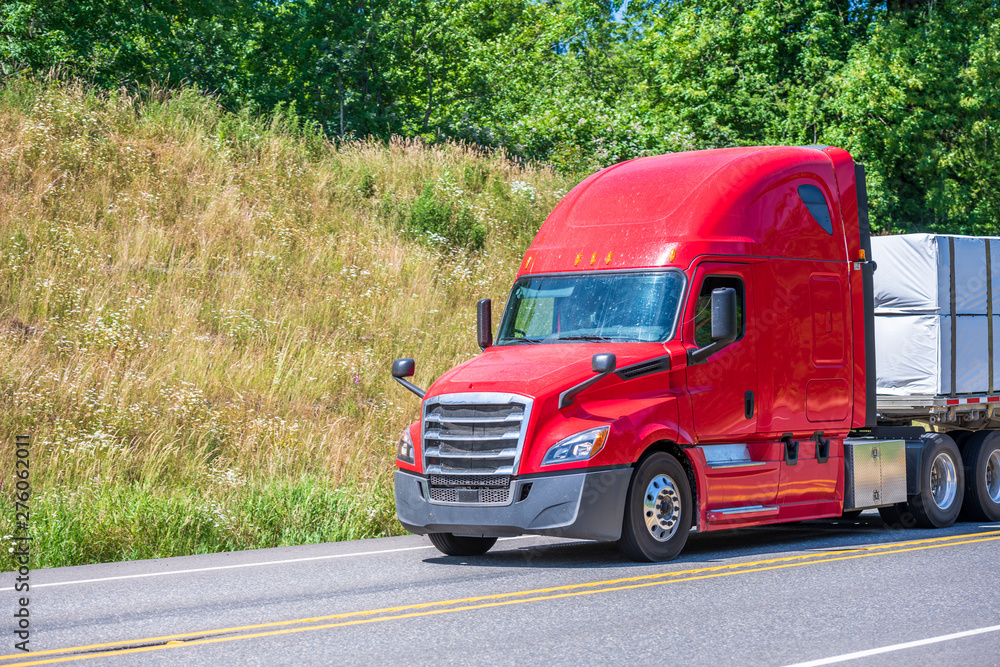 Bright red bonnet big rig semi truck transporting commercial cargo on ...