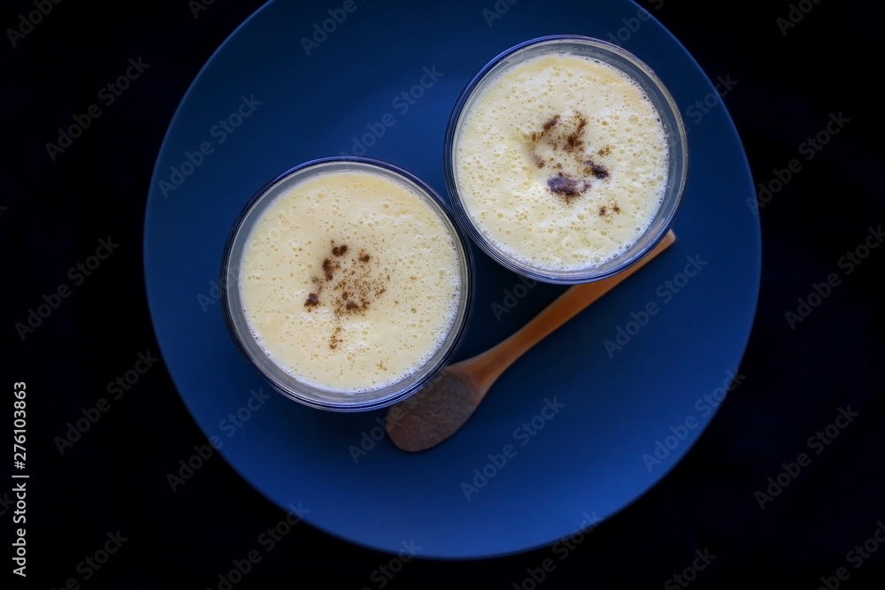 Two glasses of refreshing mango lassi drink, decorated with cardamom ...