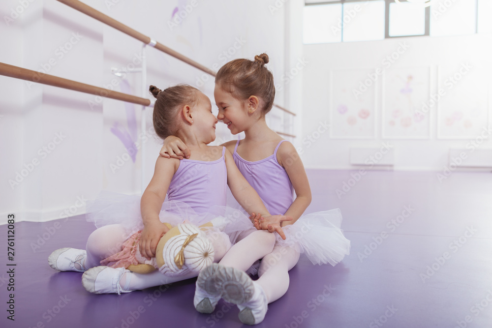 Cute young ballerina girl cuddling with her little sister at ballet ...