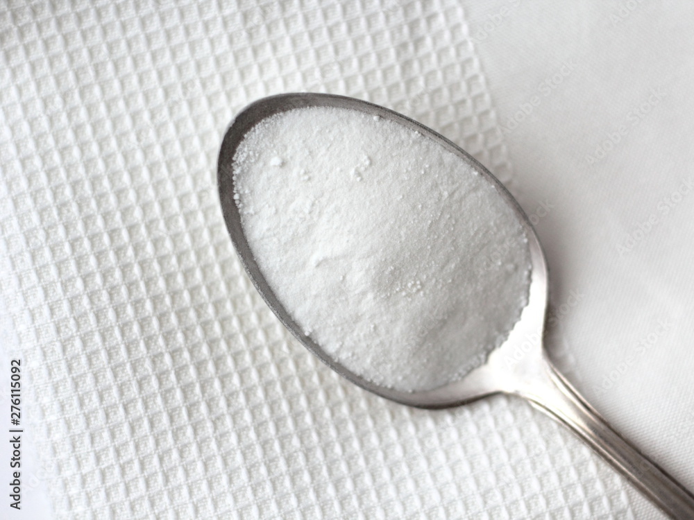 Closeup of myo-inositol powder on a spoon. Myo-inositol is a commonly ...