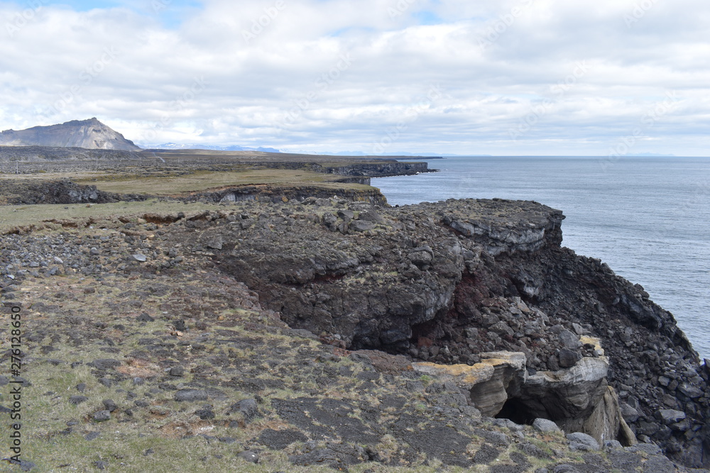 Hiking trail from Anarstapi to Hellnar with the raw ocean und big rocks and mountains in the ...