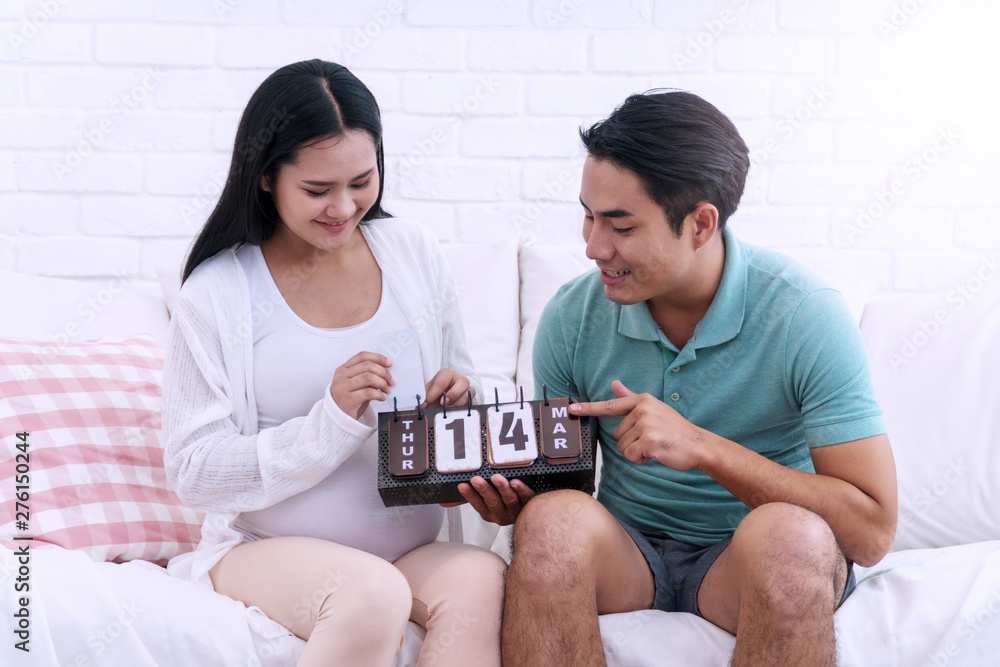 Handsome man and wife holding calendar together in hands while he use ...