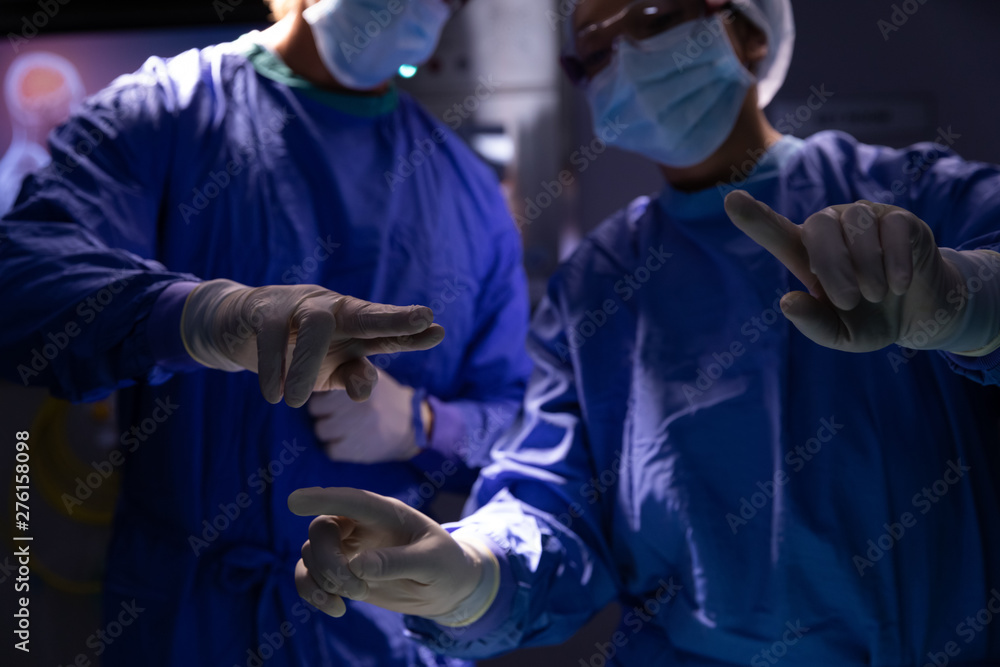 Surgeons talking with each other during surgery in operating room at ...
