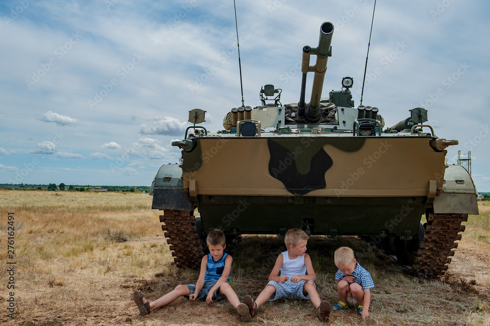 Three children in bright clothes are sitting in shade under modern ...