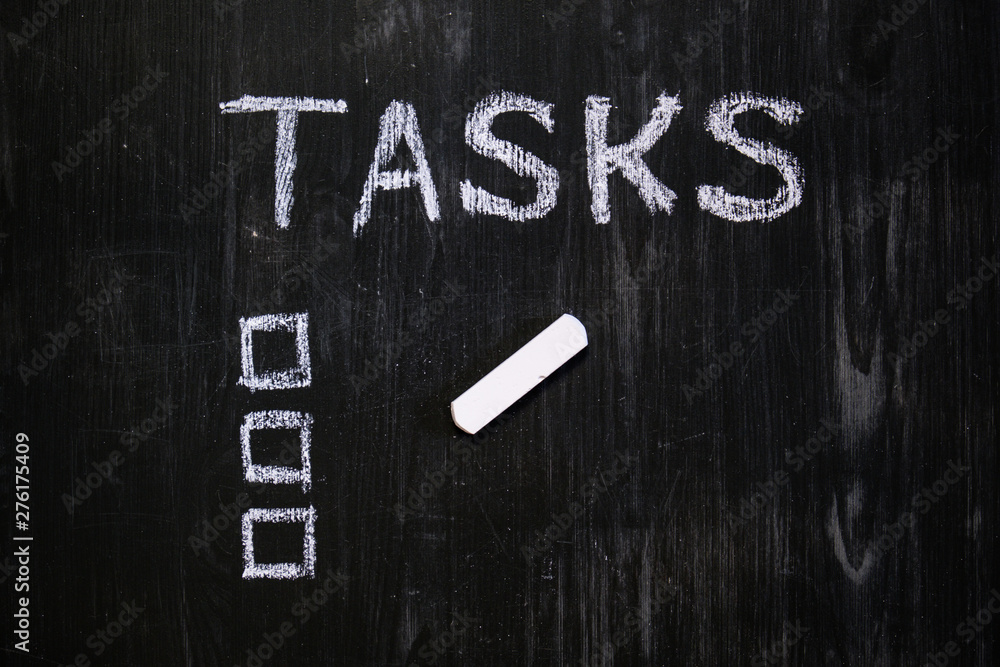 Tasks word handwritten with chalk on blackboard. Black wood background ...