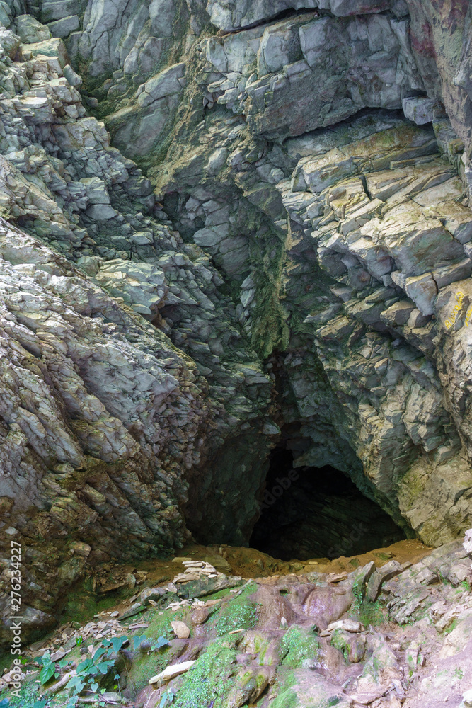 Limestone cliff wall with entrance of the cave. Cave in a layered ...