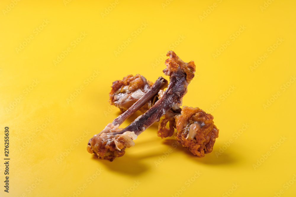 side view bones of deep fried chicken drumstick and wing on yellow ...