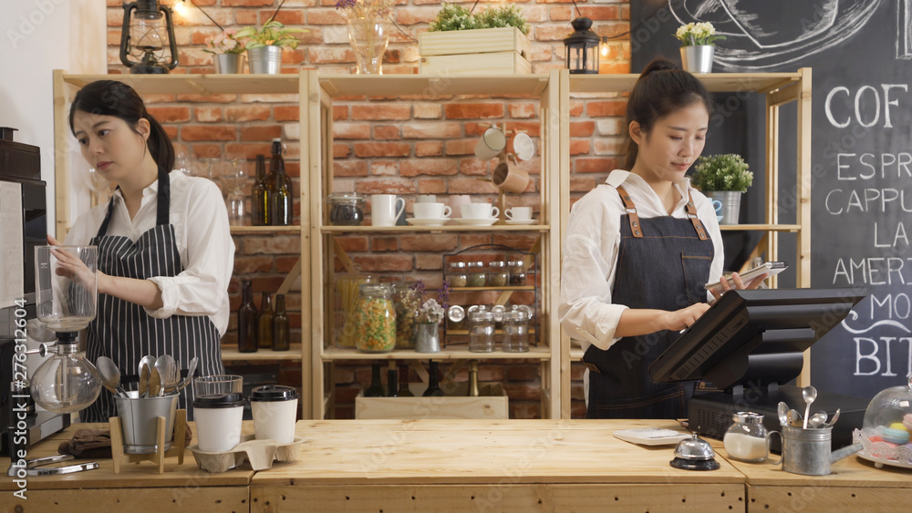 two elegant coffeehouse staff working behind counter in cafe shop ...