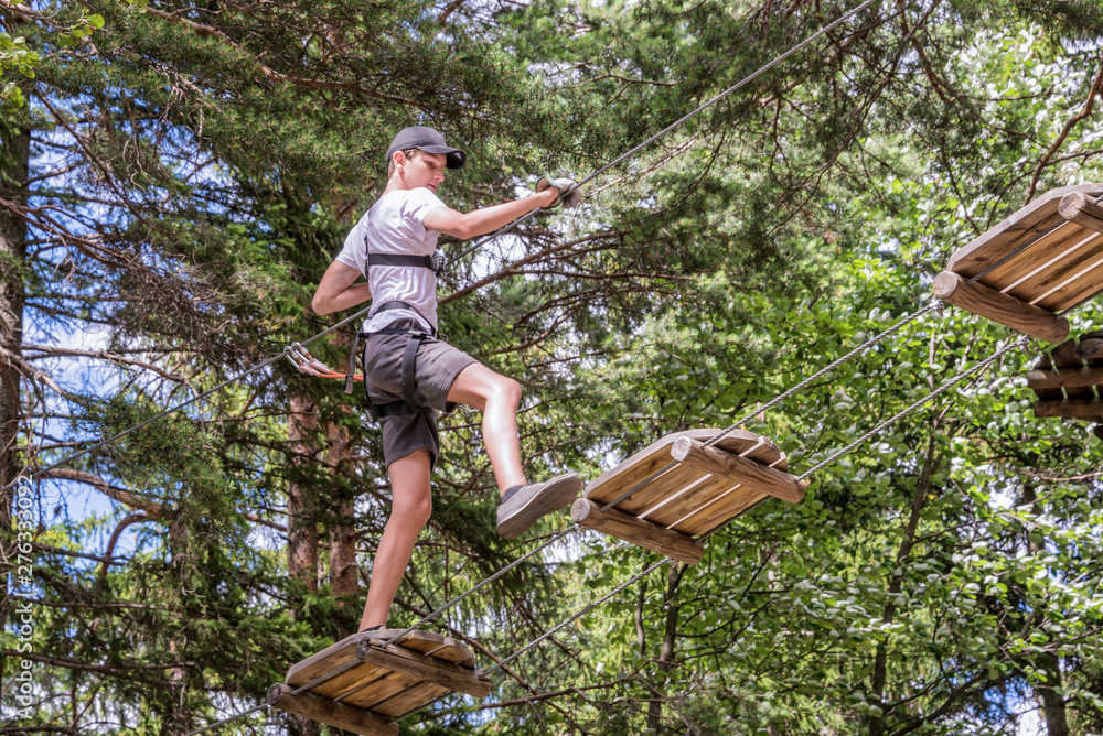 Teenager having fun on high ropes course, adventure, park, climbing ...
