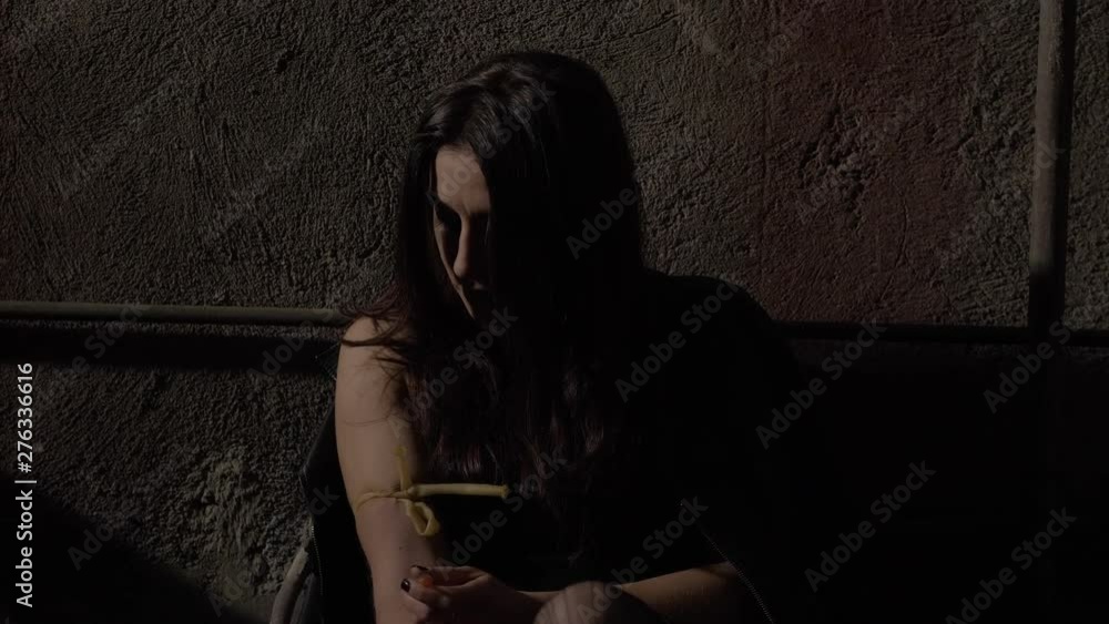 Lonely heroin addict woman in the dark injecting heroin in her veins ...