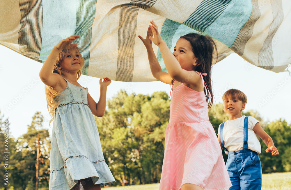 Children playing under the blanket, jumping and dancing together. Happy ...