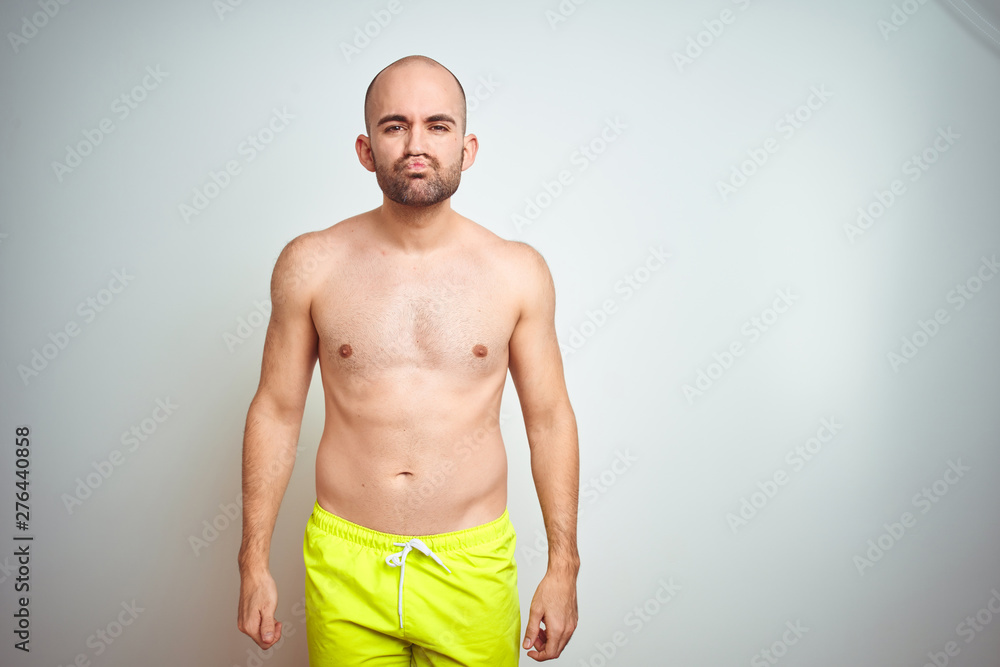 Young shirtless man on vacation wearing yellow swimwear over isolated ...