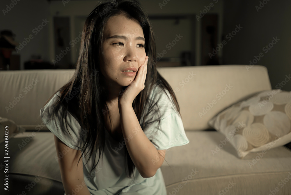 young beautiful sad and depressed Asian Japanese woman at home sofa ...
