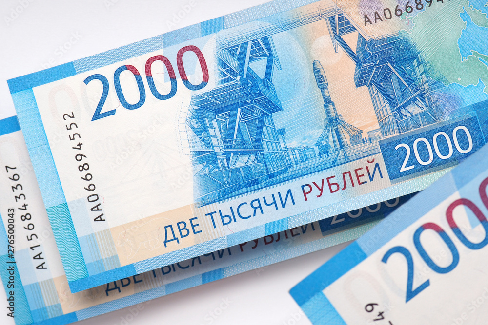 Russian banknotes of two thousand rubles hang over a white paper ...