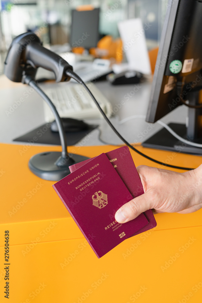 Foto de Man's hand holding two burgundy red German passports, official ...