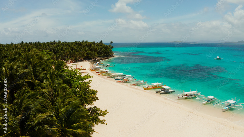Sandy beach with tourists, palm trees and turquoise water on the island ...