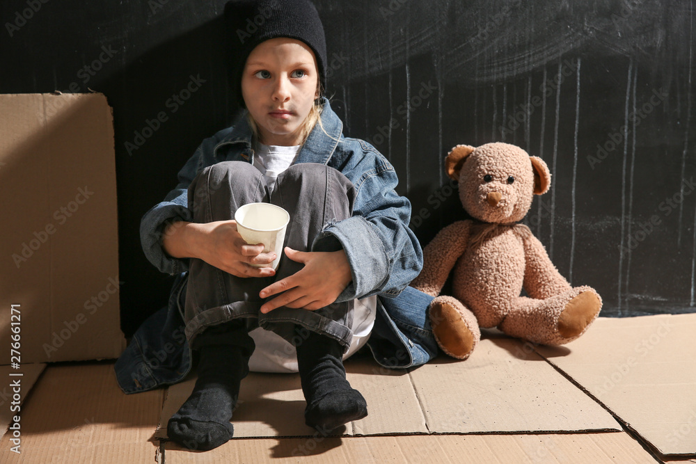 Homeless little girl sitting on floor near dark wall Stock Photo ...