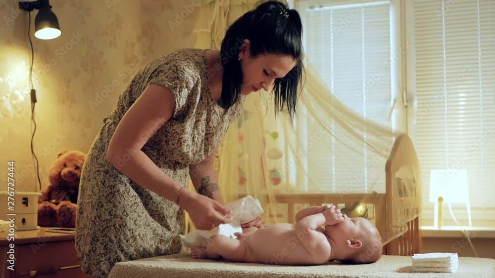 Mom changes the diaper baby. Beautiful white girl mother changes the ...