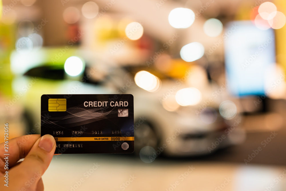 Hand holding credit card with blur car showroom in shopping mall ...