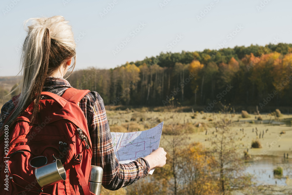 Tourism and adventures. Back view of lady with backpack using map to ...