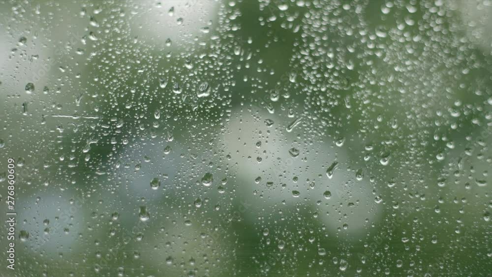 4k Close-up footage of raindrops splashing against a window glass with ...