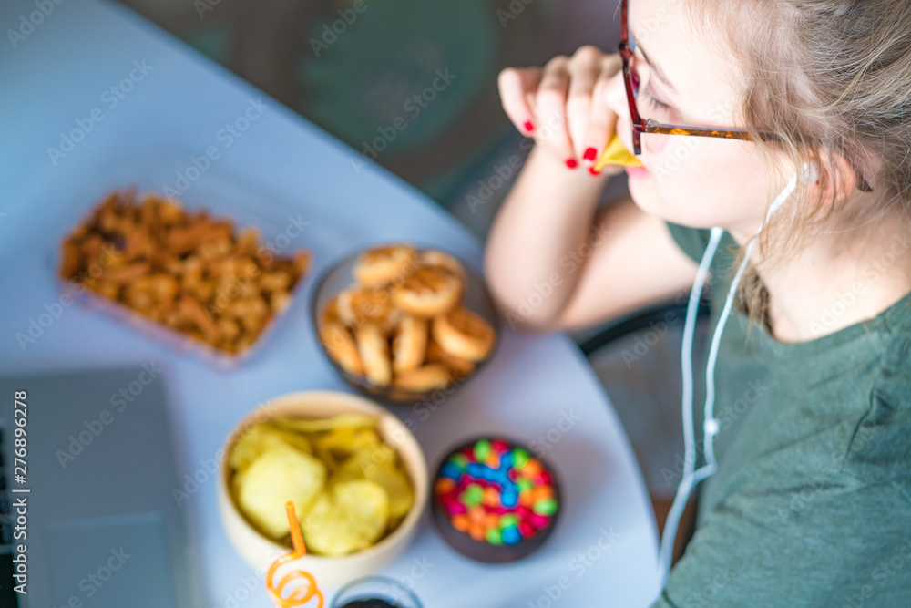 Girl works at a computer and eats fast food. Unhealthy food: chips ...