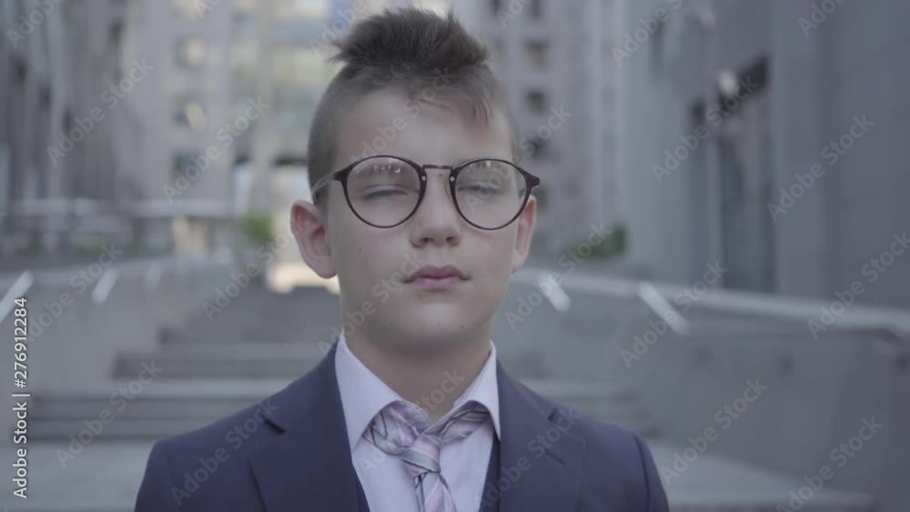 Portrait handsome well-dressed boy in spectacled standing on the street ...
