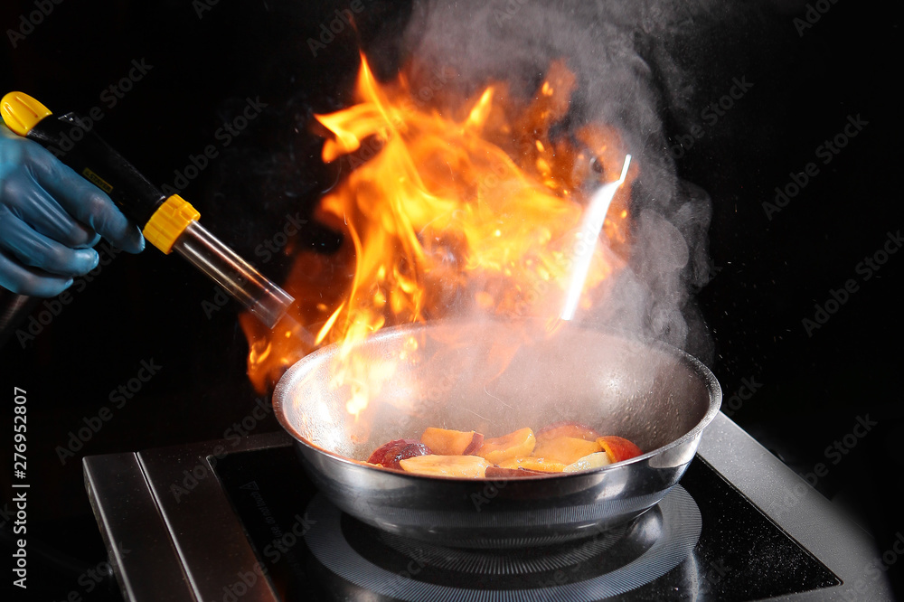 Flame over the pan when cooking flambe fruit. Food show for restaurant ...