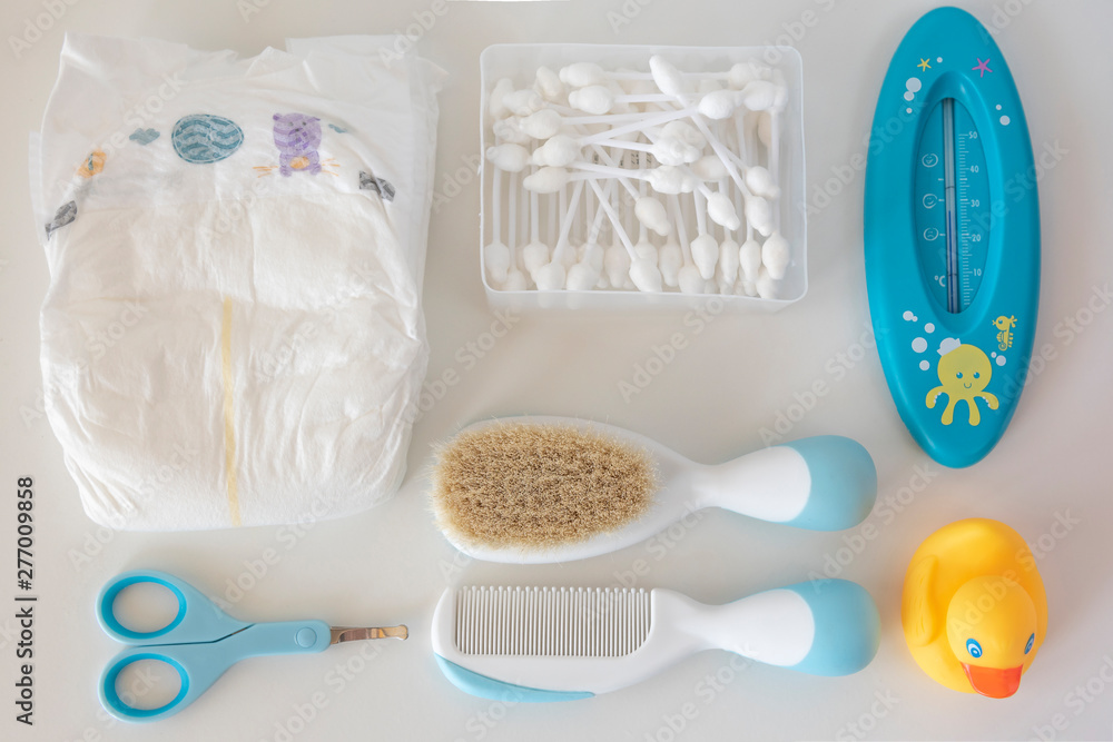 Baby essentials for hygiene concept: diapers, cotton swabs, scissors ...