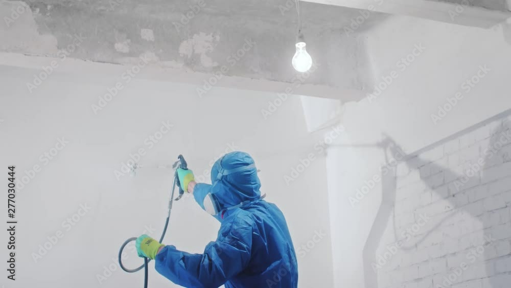 Airless Spray Painting. Worker painting the wall by airless spray gun ...