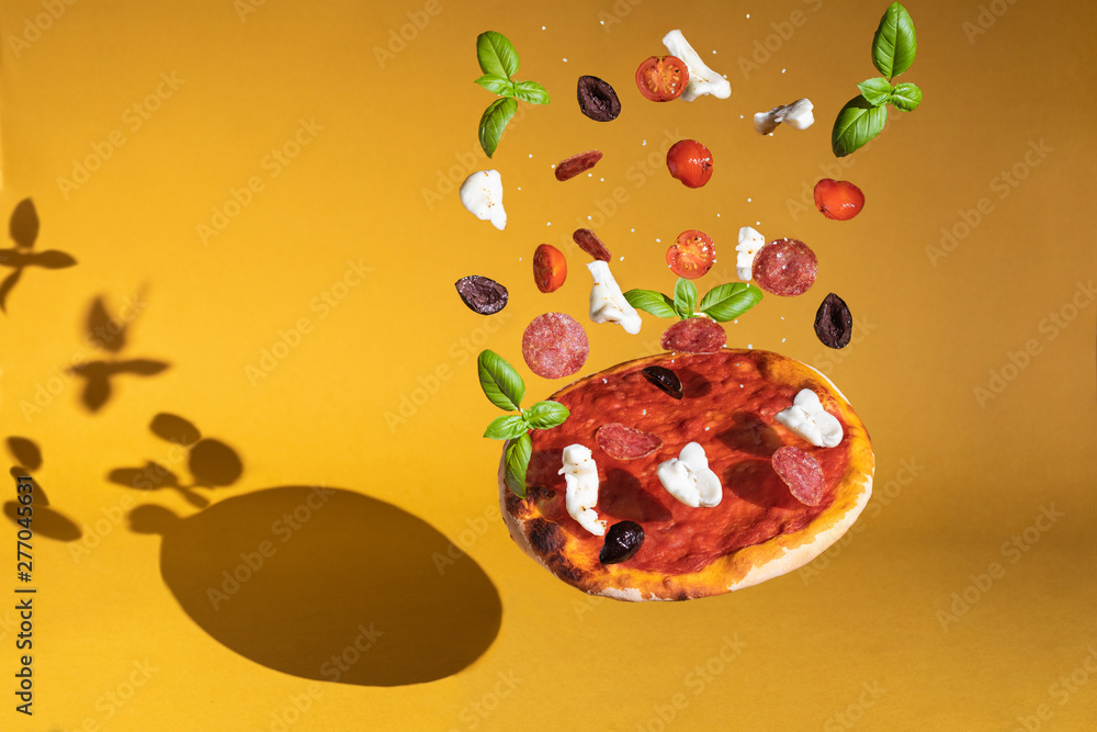 Pizza fly. Flying ingredients with pizza dough on yellow background ...