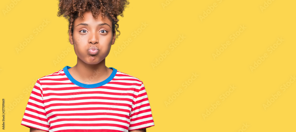 Beautiful young african american woman over isolated background puffing ...
