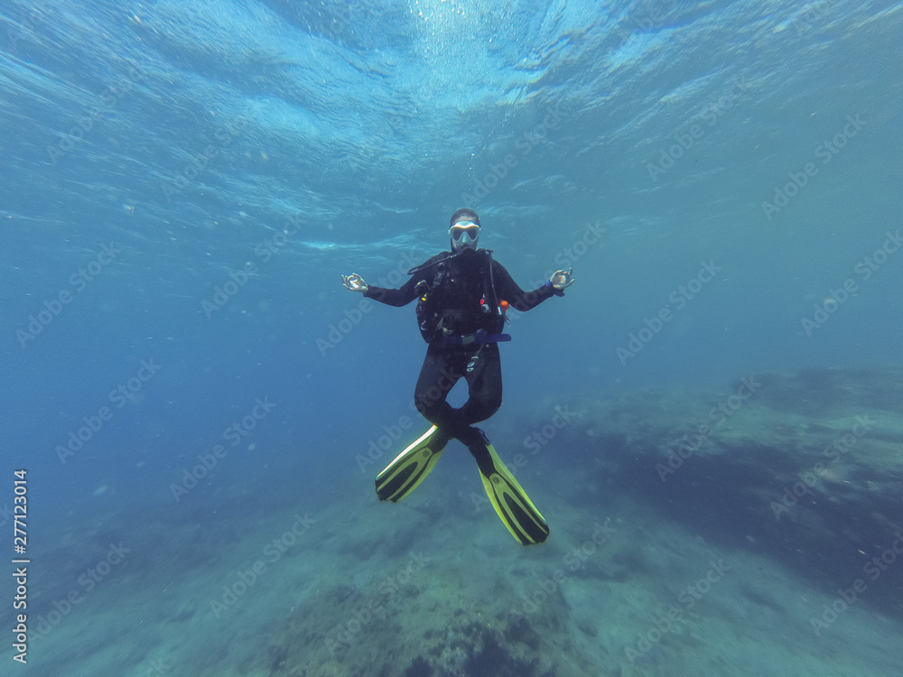 Young female scuba diver in the lotus yoga position during a dive in ...