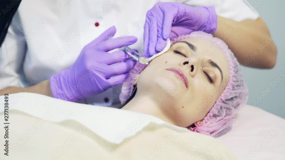 Beautician makes a skin prick on face for young woman using syringe ...