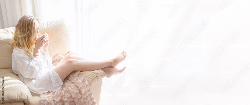 Woman sitting in white armchair and drinking coffee at the morning in ...