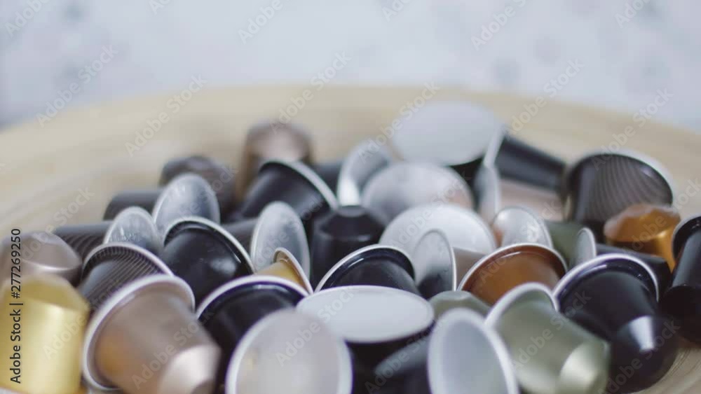 Guy's hand is taking small, black, round-shaped coffee capsule out of ...
