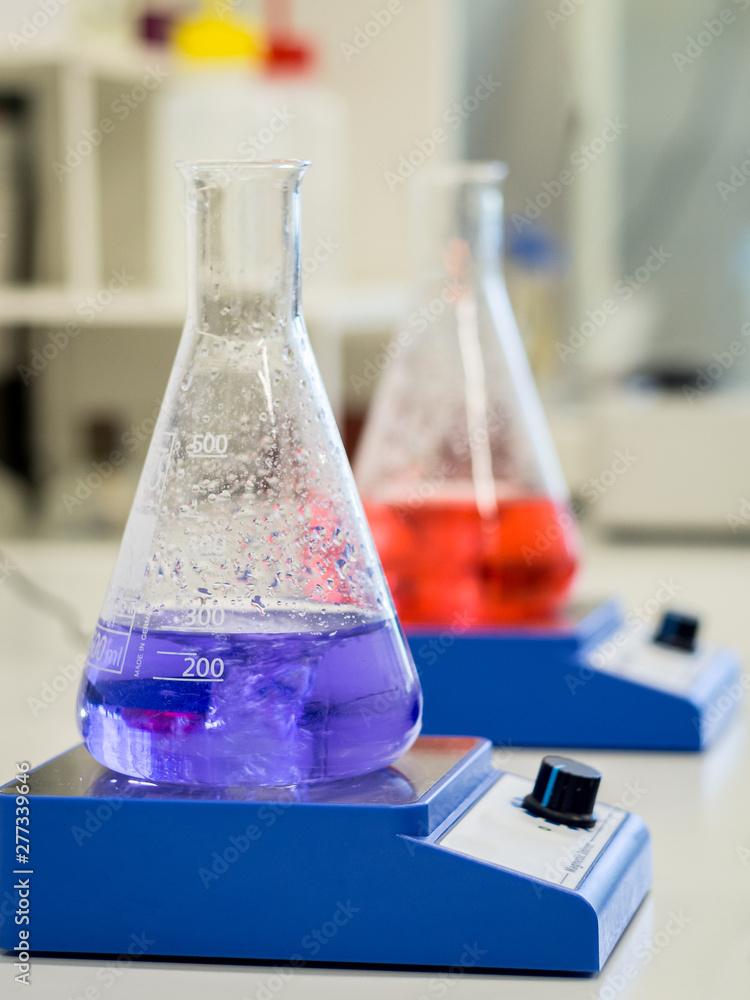 Erlenmeyer flasks with colorful solutions on a magnetic stirrer in a ...