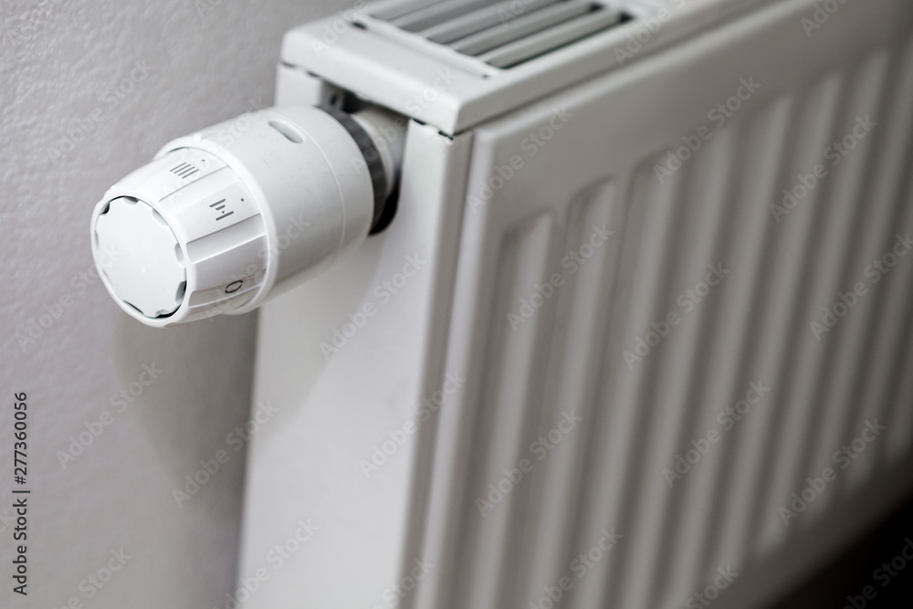 white temperature control knob on white radiator. metal radiator on the ...